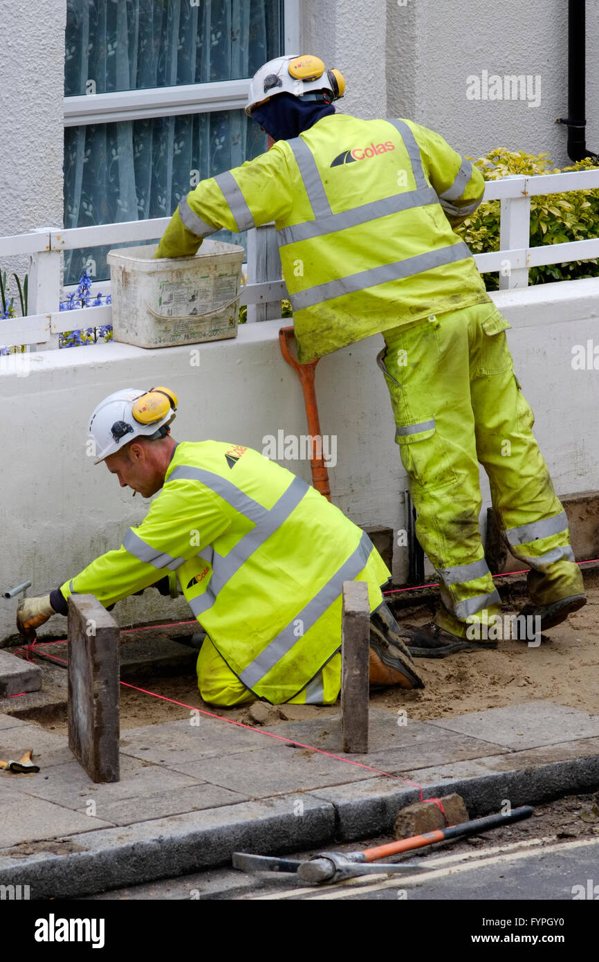 workmen replacing a pavement in urban side street in southsea england ...