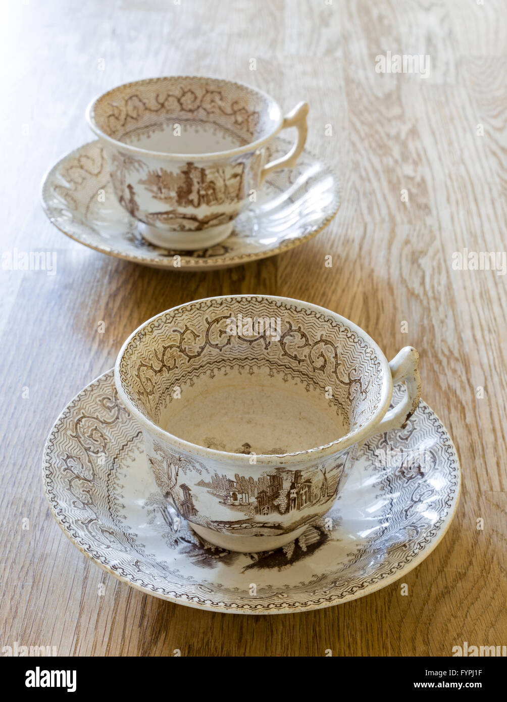 Two old antique porcelain coffee or tea cup and saucer on wooden table ...