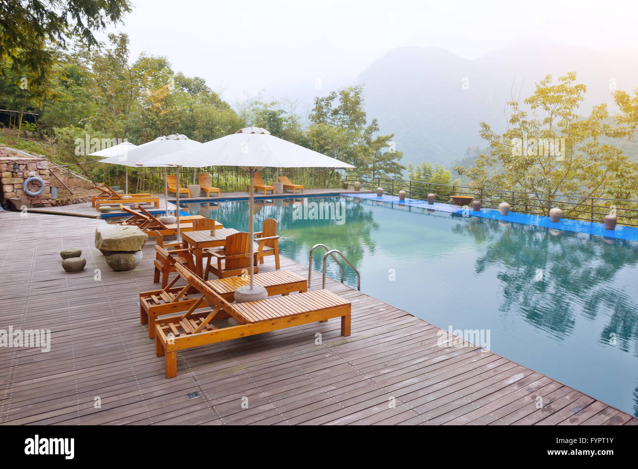 Umbrella chair in hotel pool resort with sunset Stock Photo - Alamy