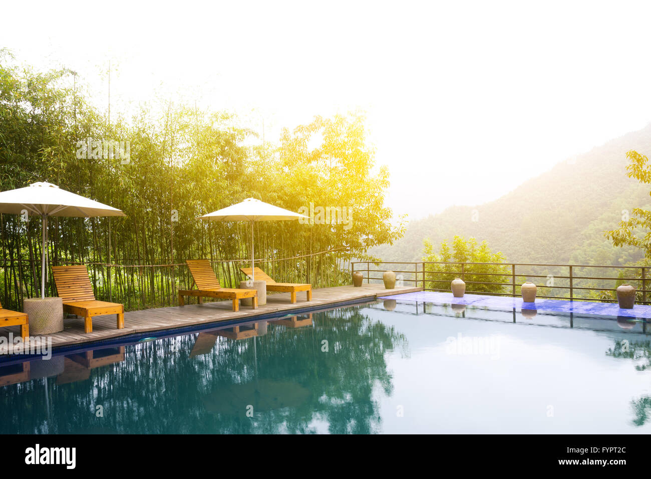 Umbrella chair in hotel pool resort with sunset Stock Photo - Alamy
