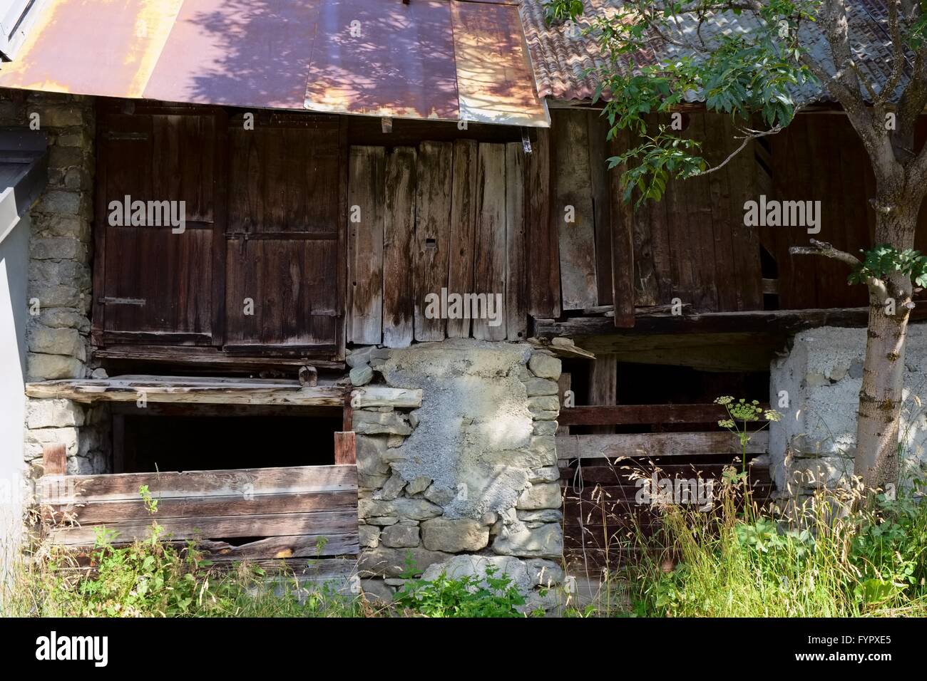 Detailed facade view of a ramshackle ruined barn of boulders, wood and ...