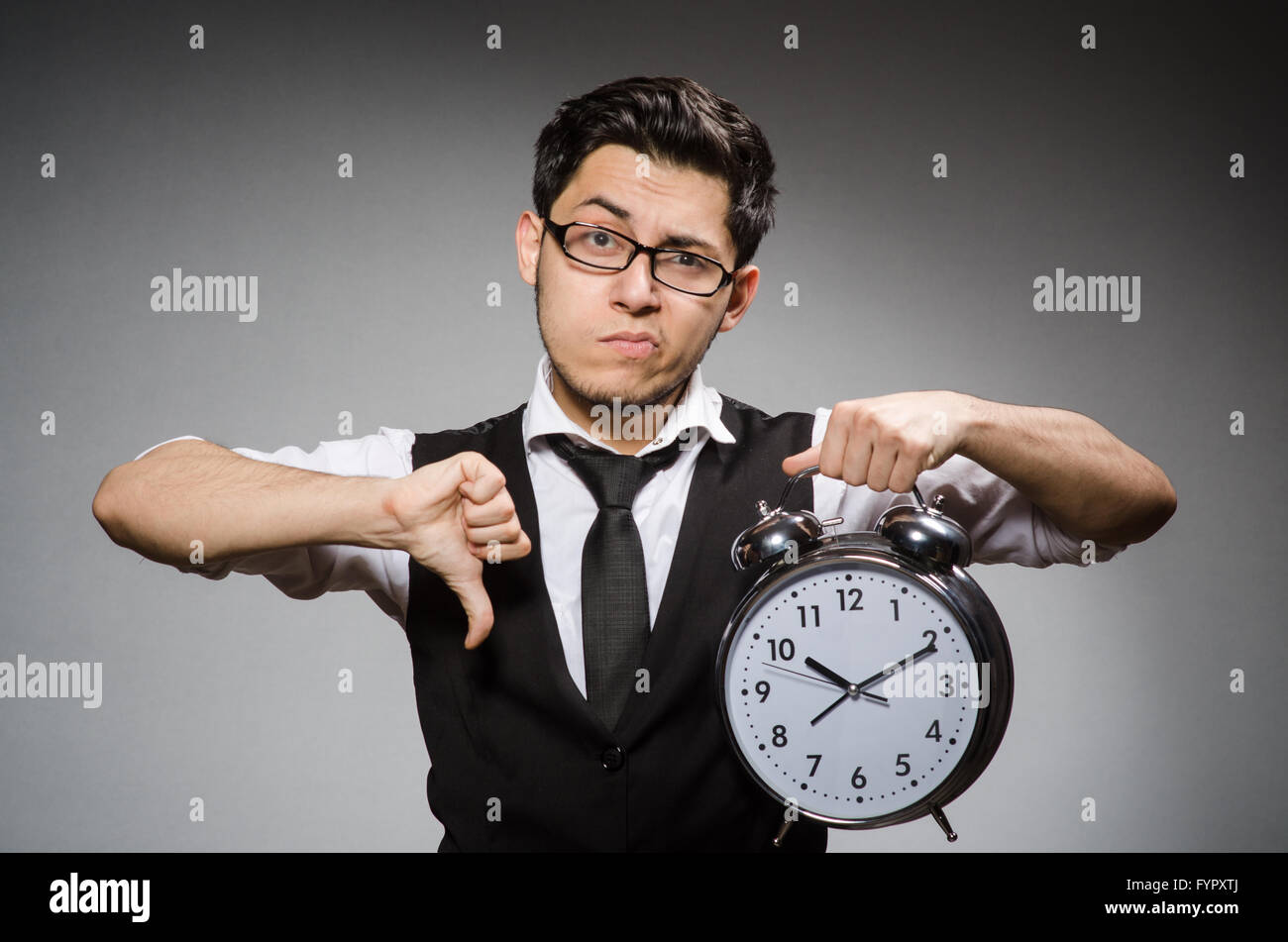 The employee holding alarm clock against gray Stock Photo - Alamy