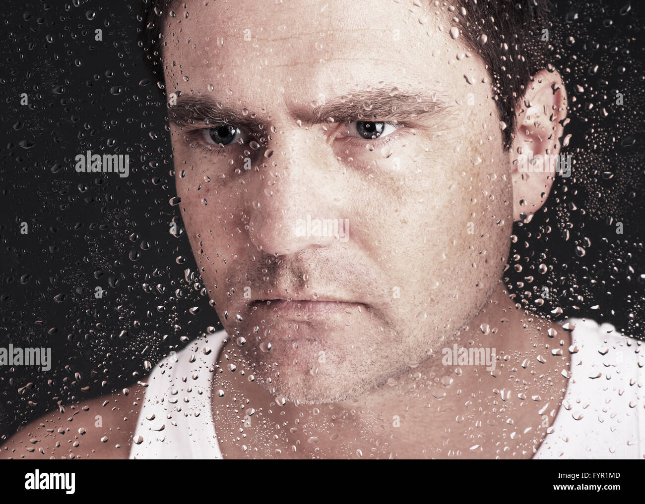 Closeup of pensive man looking through window covered with raindrops ...