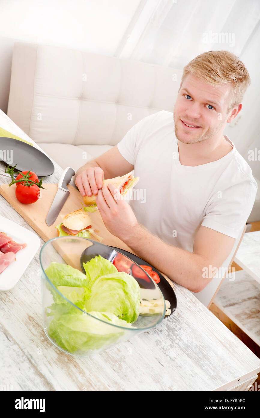 Young man eating a sandwich at home Stock Photo - Alamy
