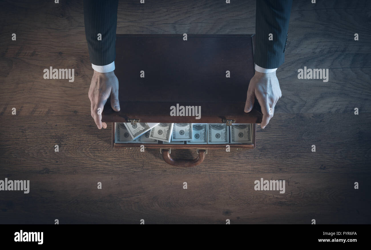 Rich businessman opening a leather briefcase filled with dollar packs ...