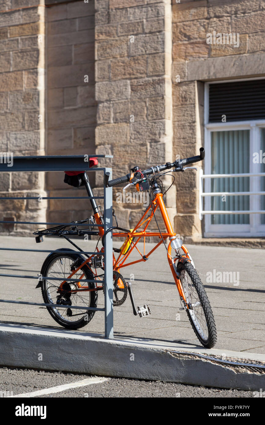 An orange Moulton Space frame small wheel bike locked to a fence in ...