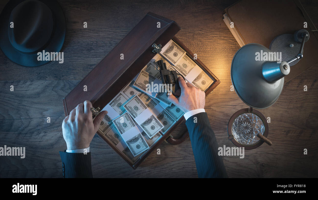 Vintage gangster with a gun and a leather briefcase filled with dollar ...