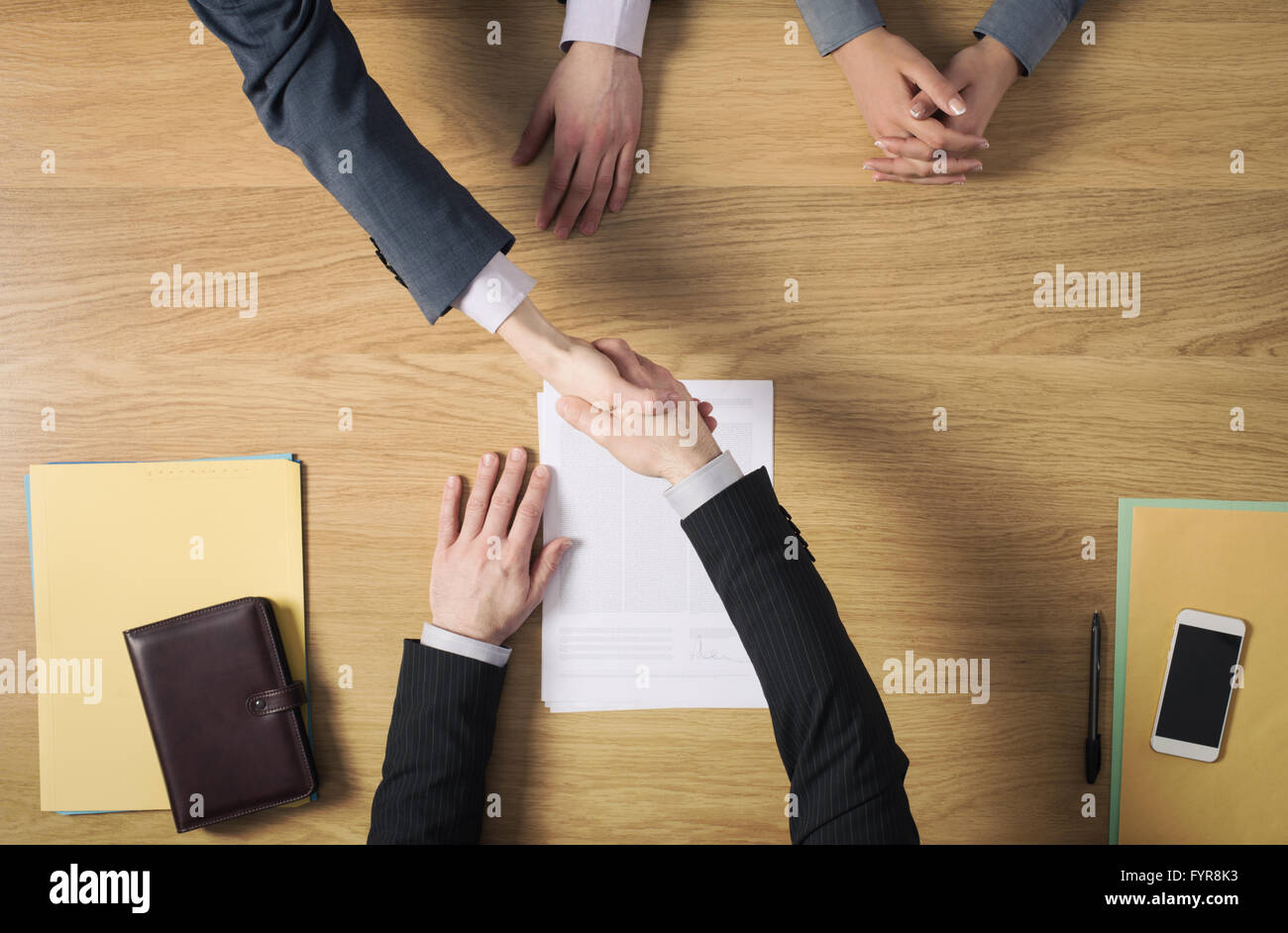 Business people at office desk handshaking after signing an agreement ...