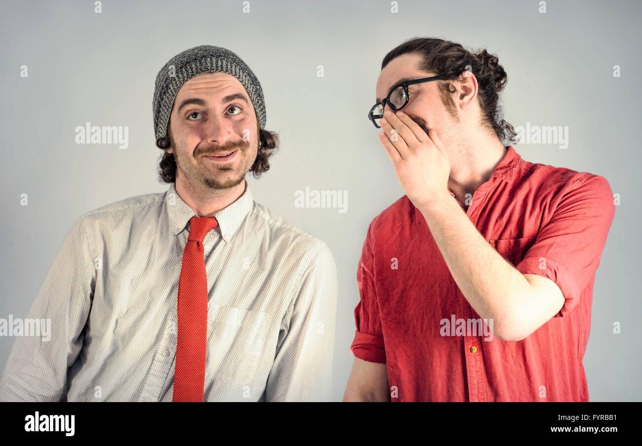 Twin adult men with beards tell secrets to eachother Stock Photo - Alamy