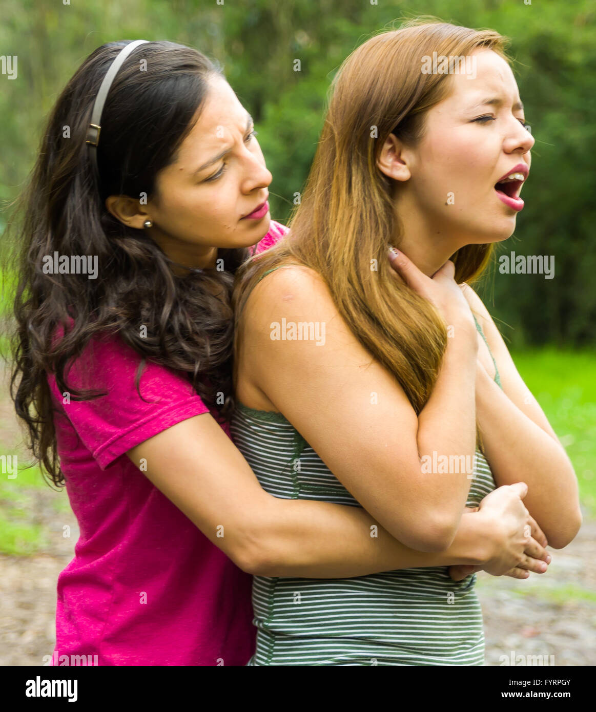 Young woman choking with lady standing behind performing heimlich ...