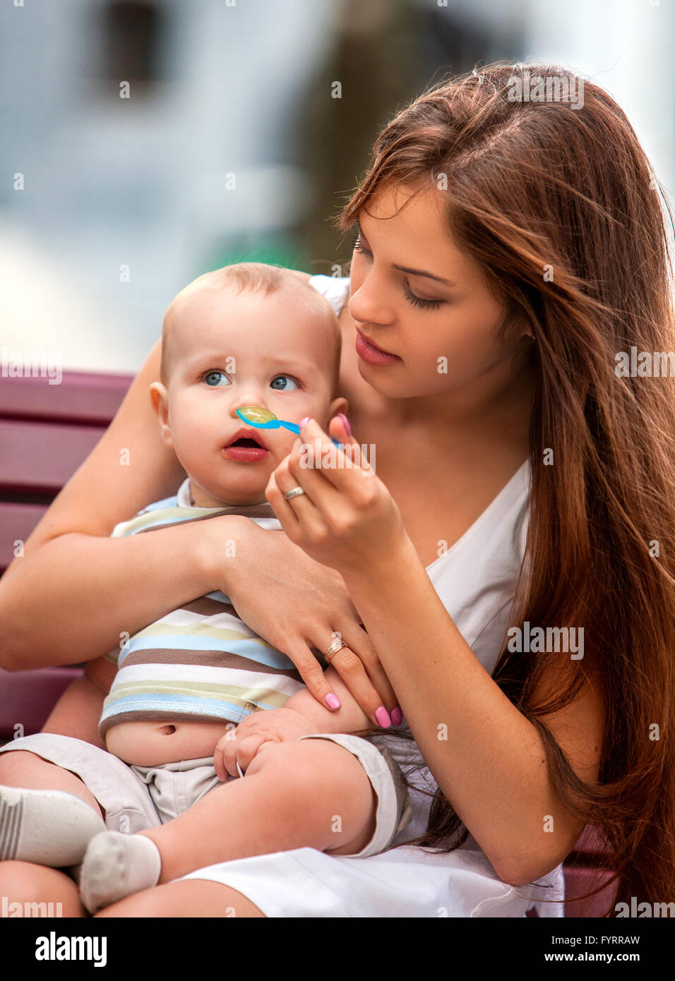 Portrait of happy beautiful mother feed her baby summer outdoors in ...