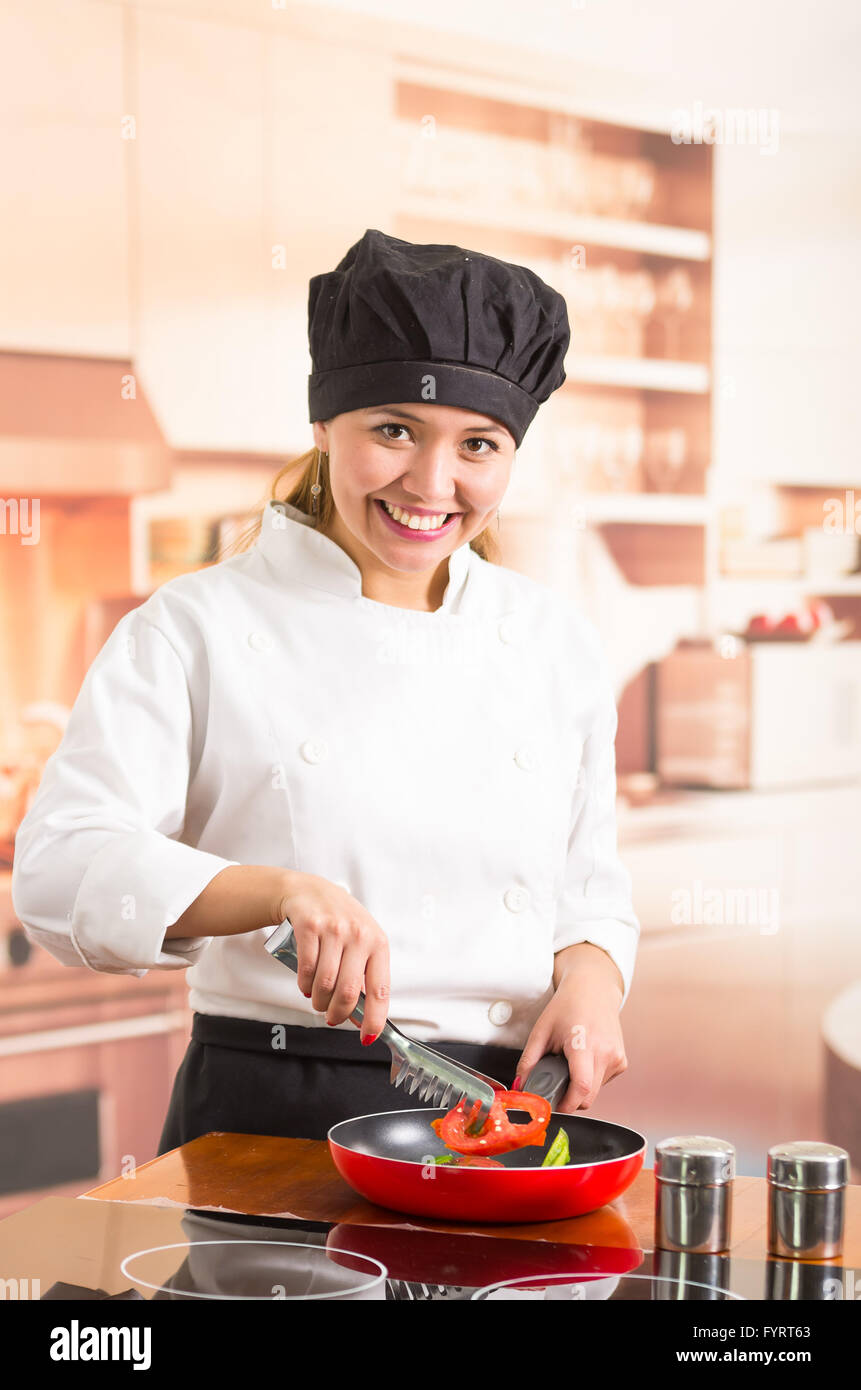 Woman chef wearing full cooking outfit standing frying vegetables in ...
