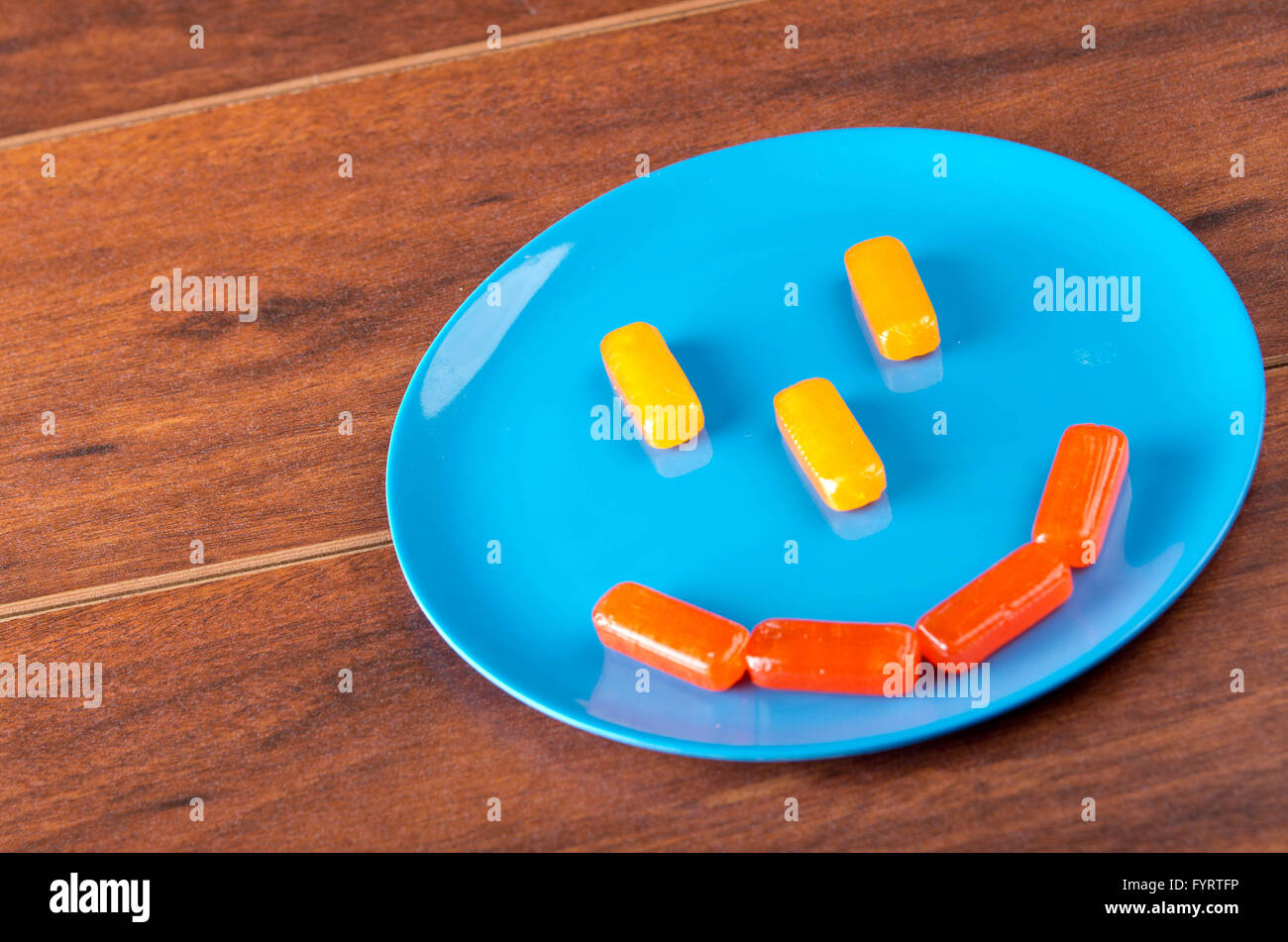 Colorful rectangular hard candy placed as smiley face on blue plate ...