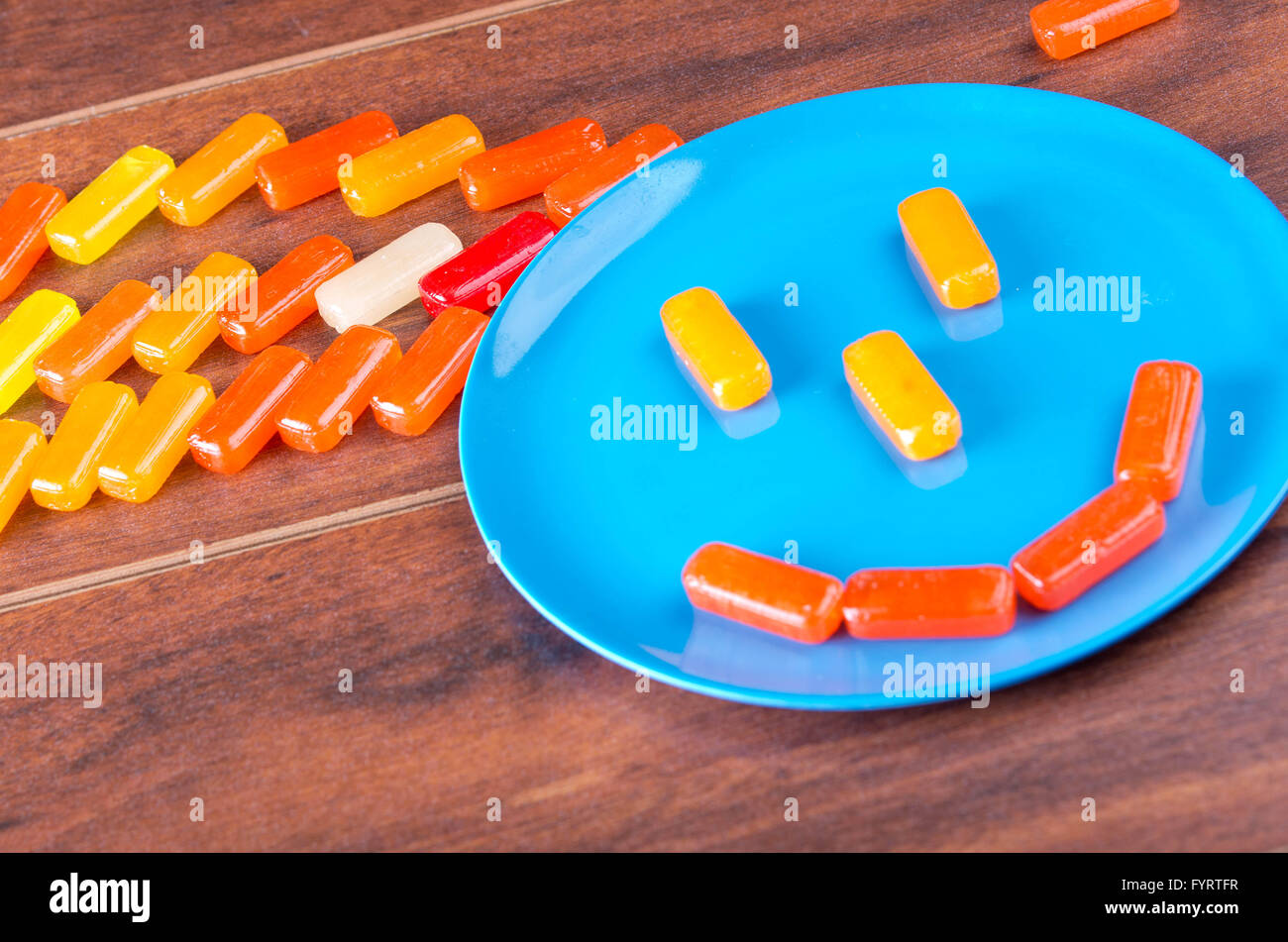 Colorful rectangular hard candy placed as smiley face on blue plate ...