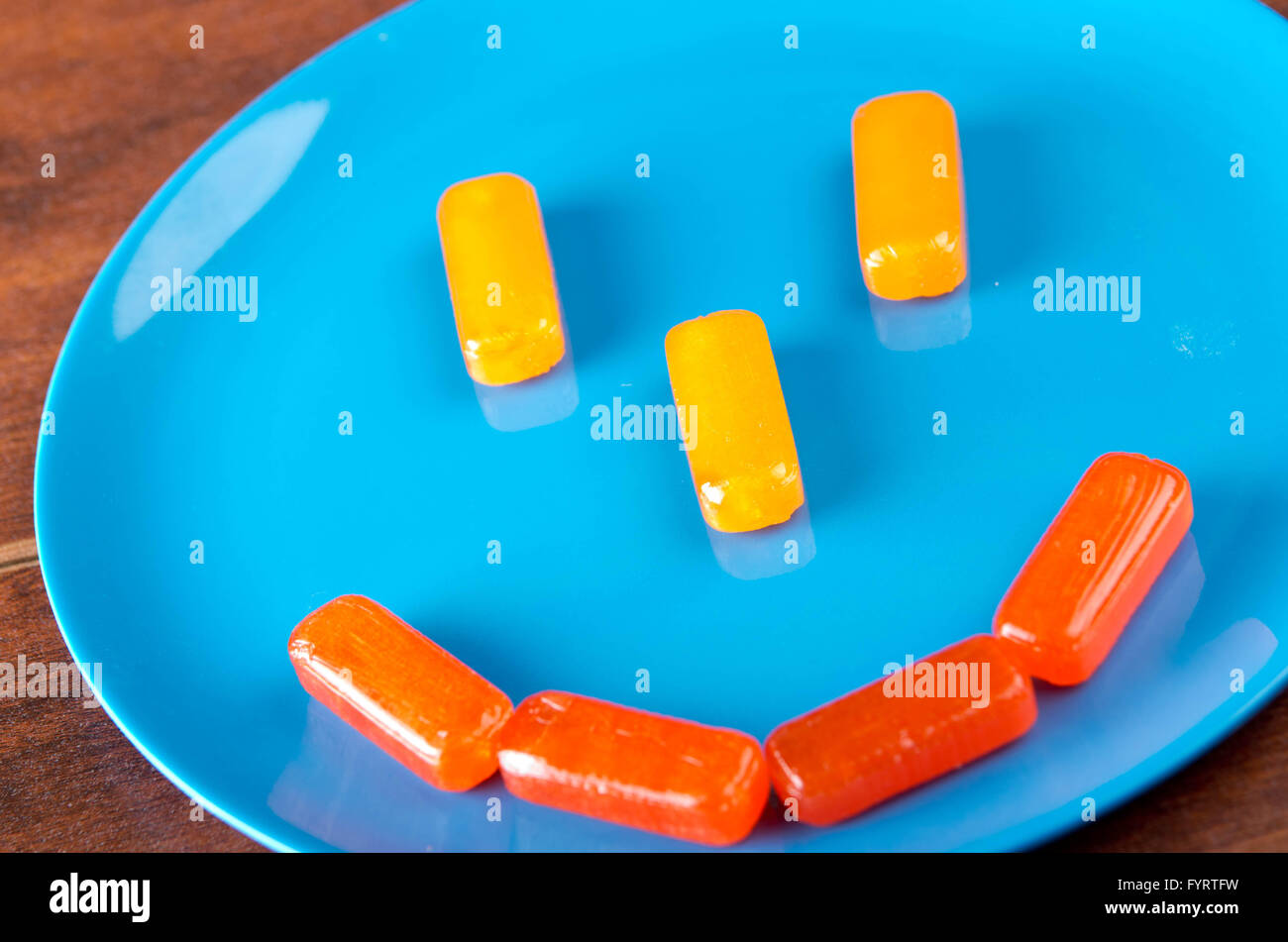 Colorful rectangular hard candy placed as smiley face on blue plate ...