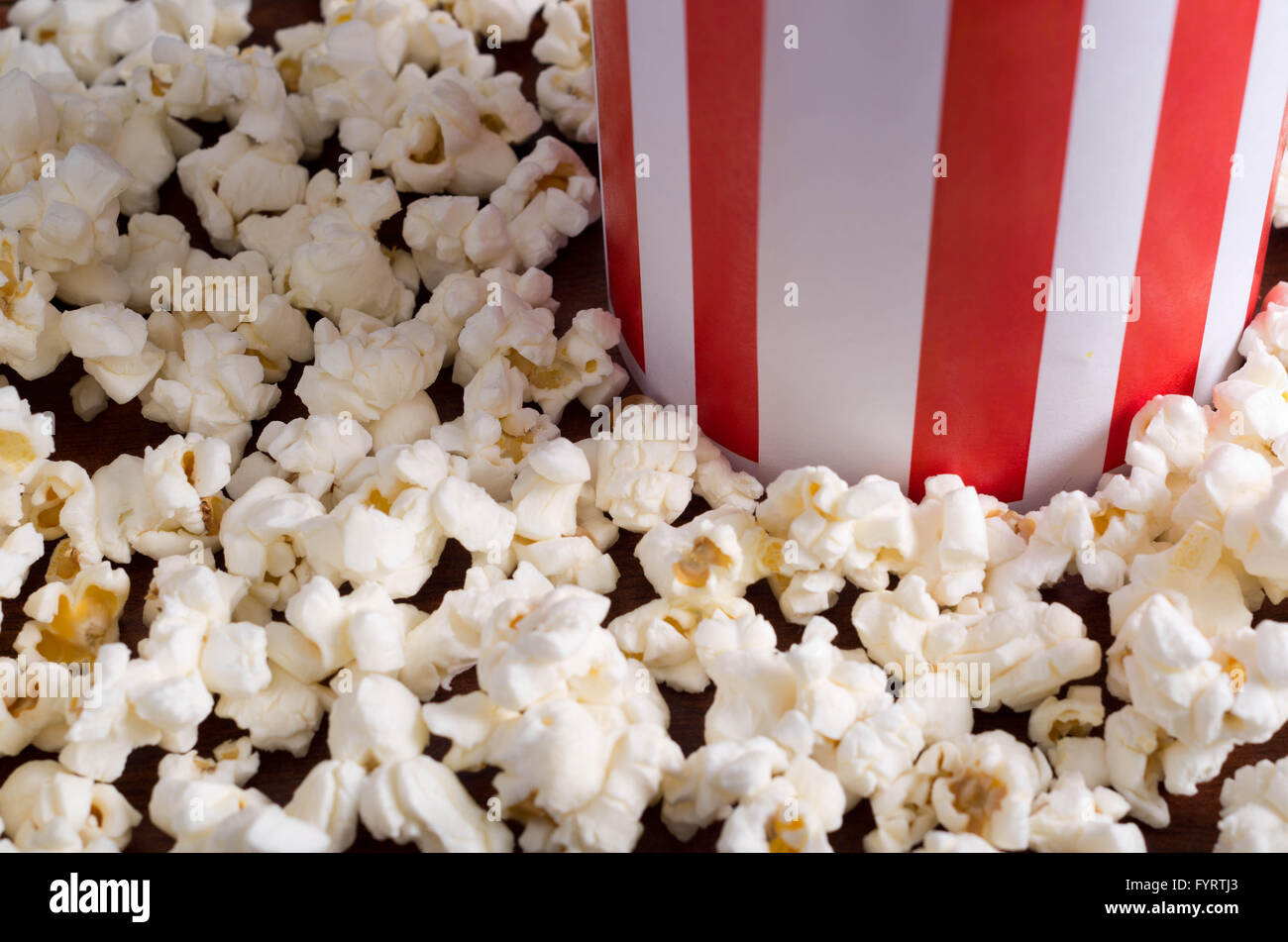 Closeup red white striped container box standing up with popcorn lying ...
