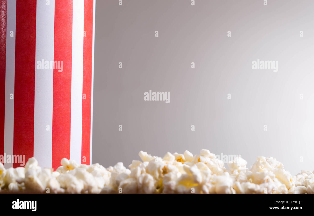 Closeup red white striped container box standing up with popcorn lying ...