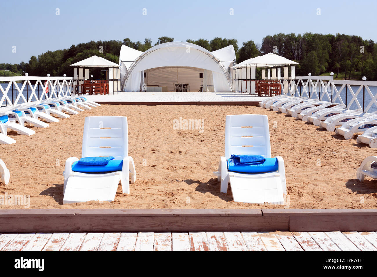 Summer vacation. Outdoor solarium with empty plastic beach chairs near ...