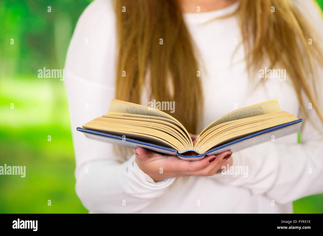 Closeup open book held by woman wearing white sweater and long hair ...