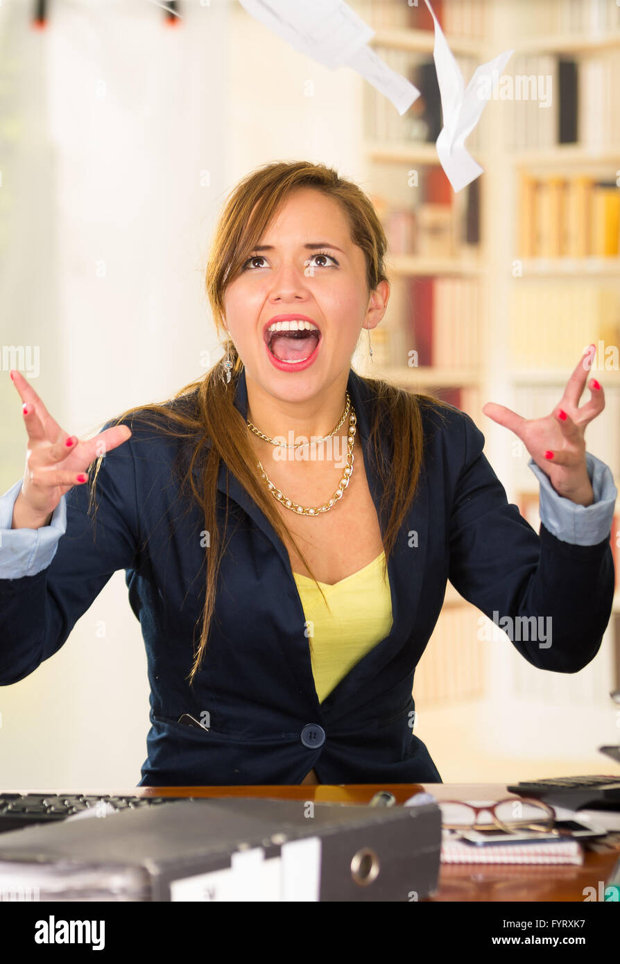 Office woman sitting by desk throwing papers up in the air and ...