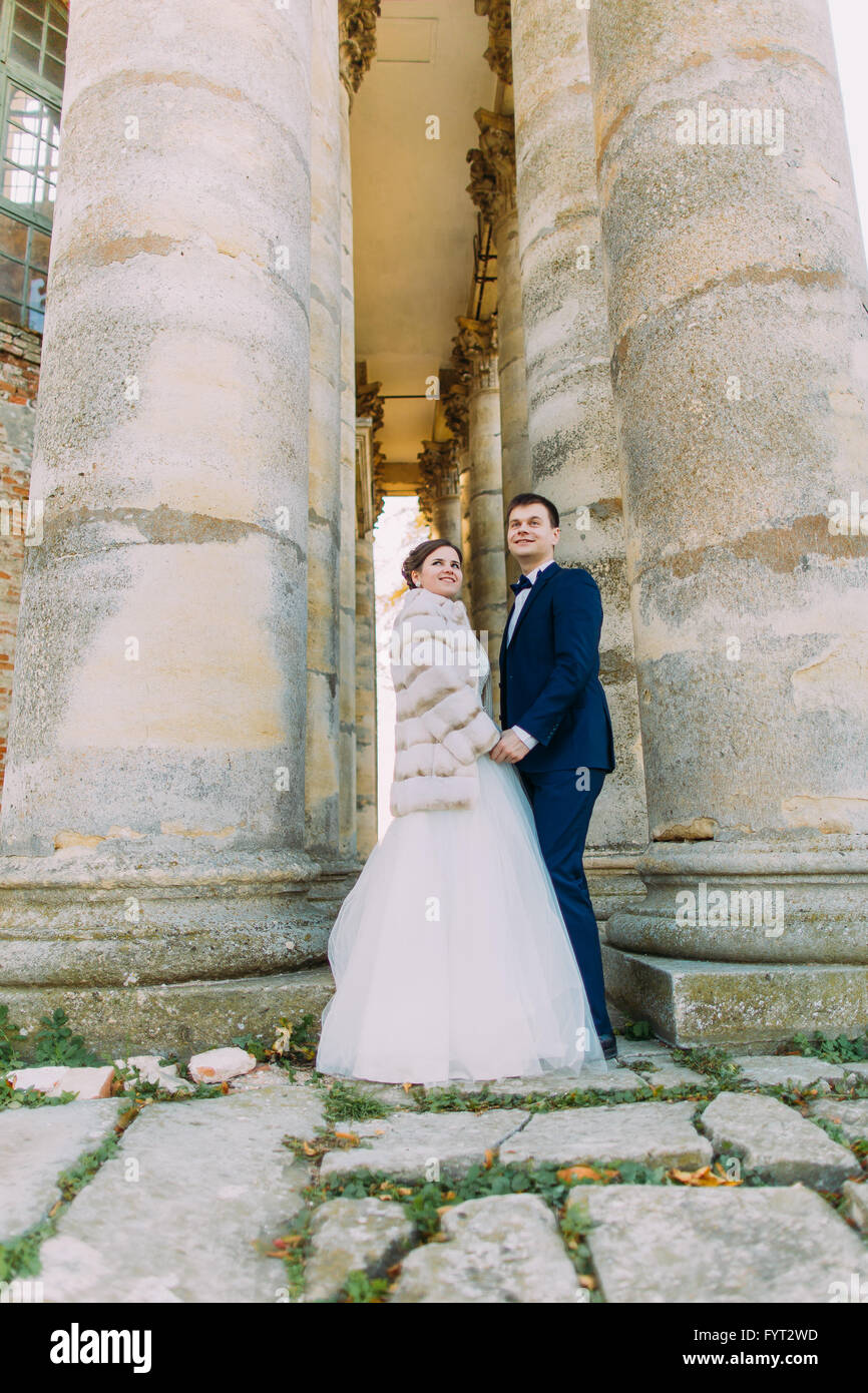 Handsome groom and his beautiful bride in white dress standing holding ...