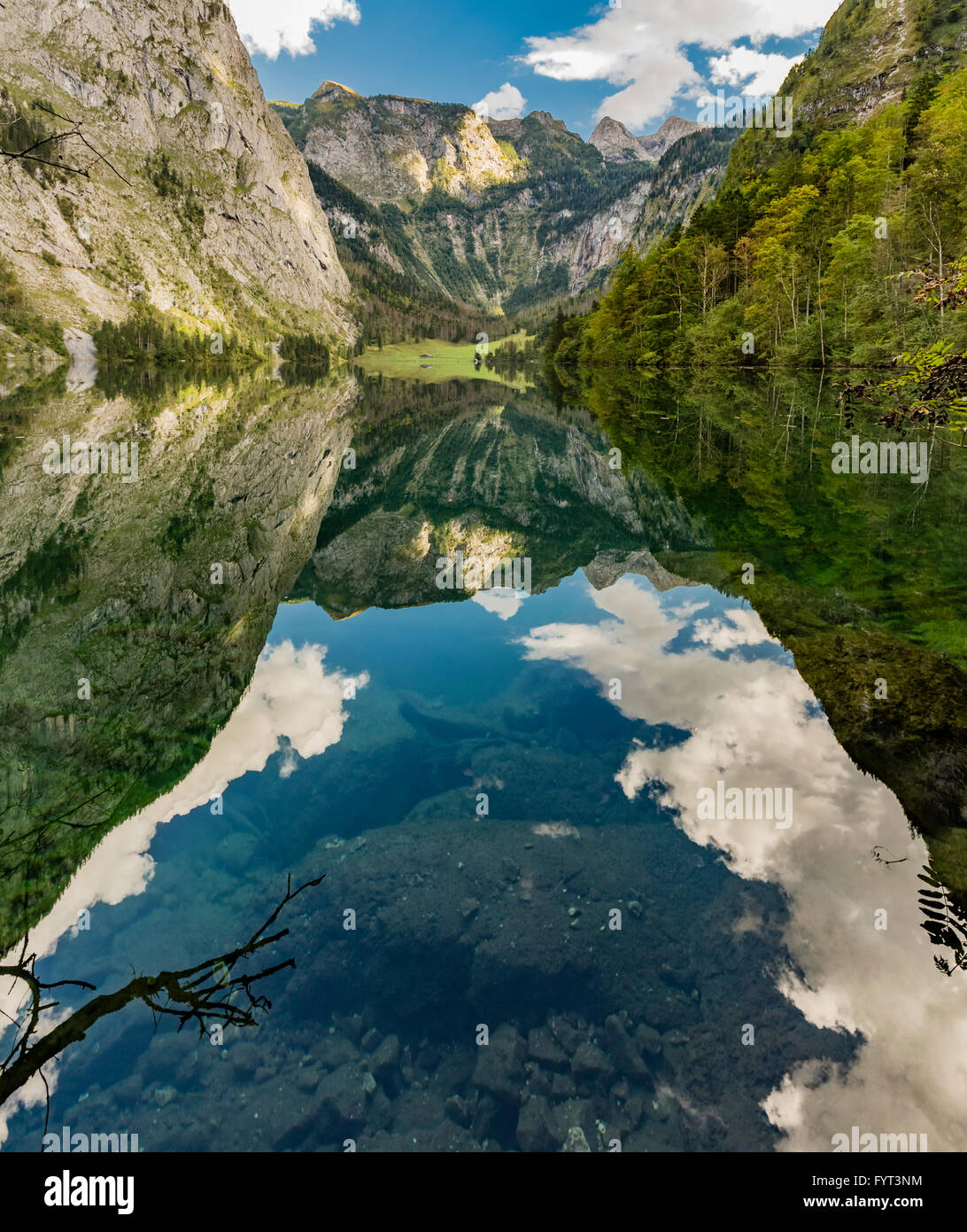 Reflection of blue sky and mountains in calm mountain lake with trees ...