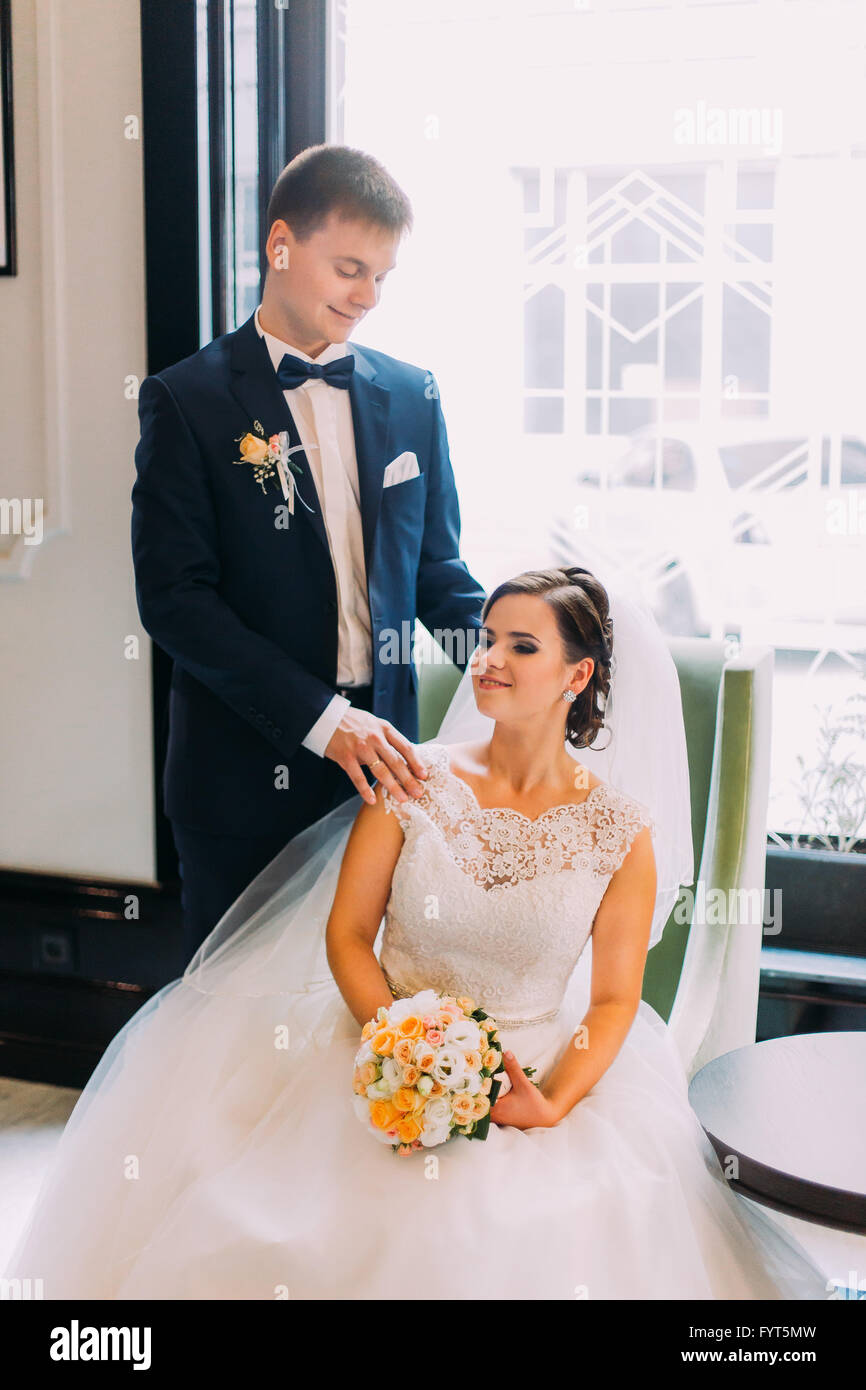 Handsome groom hugging from back bride with big wedding bouquet in the ...