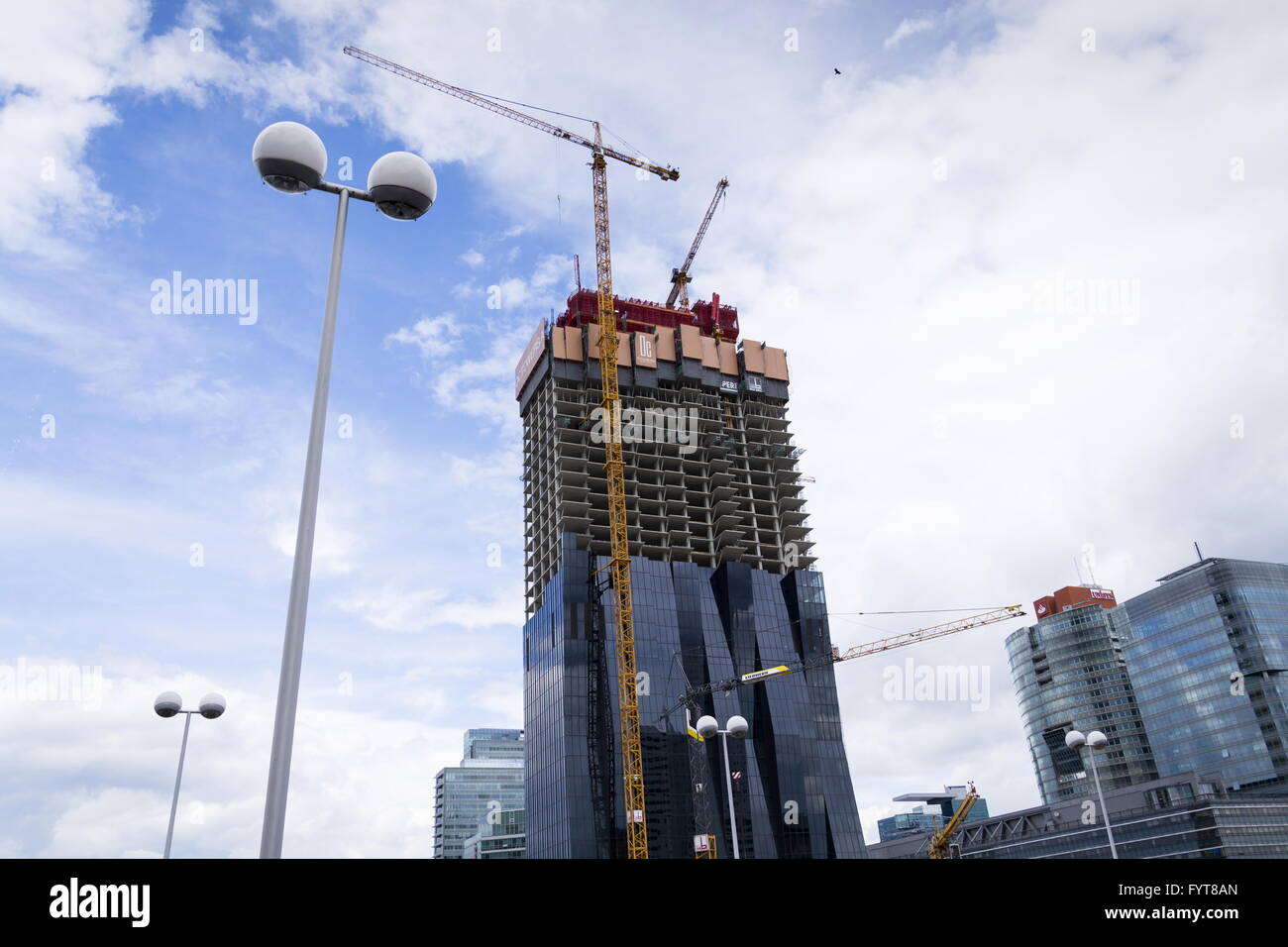 Yellow crane on skyscraper construction site with windows reflecting ...