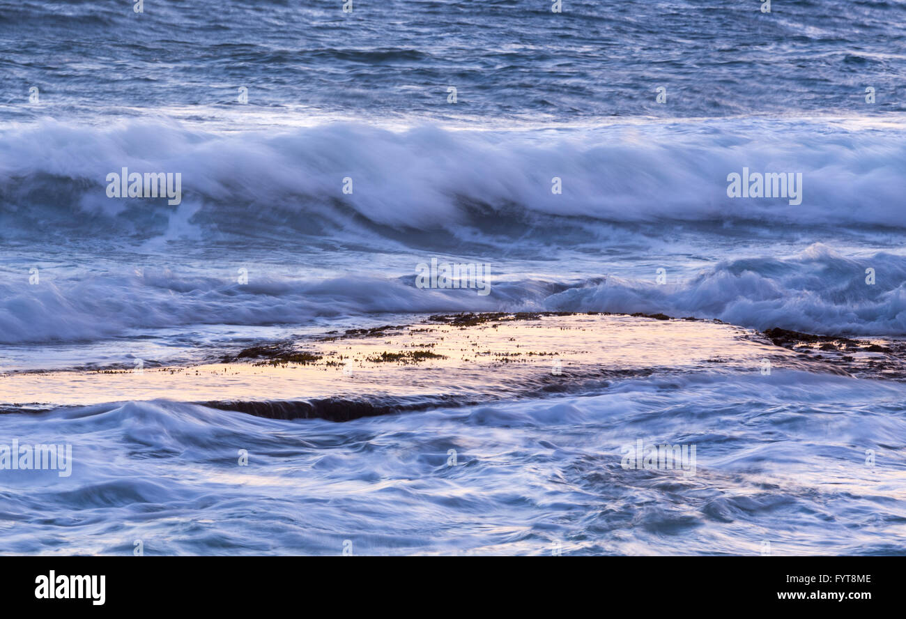 Ocean waves splash over calm rock shelf at dawn Stock Photo - Alamy