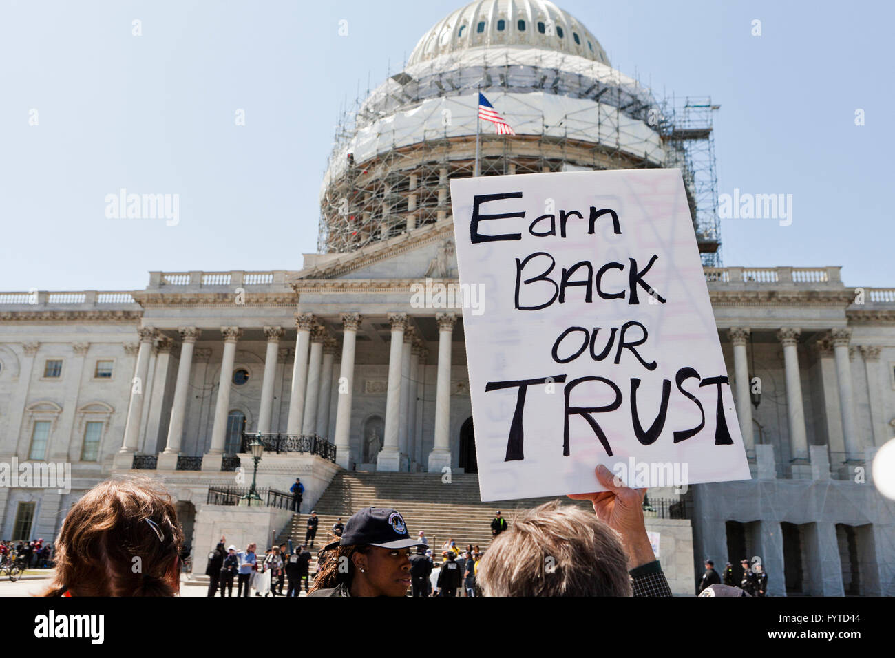 Progressive activist holding "Earn Back Our Trust" sign in front of the ...