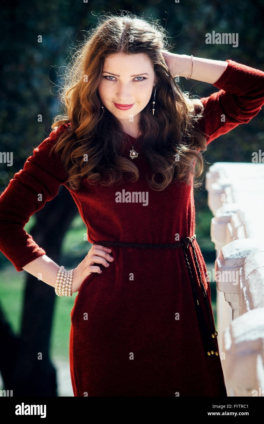 Portrait of attractive young woman in bright red dress in sunlight ...