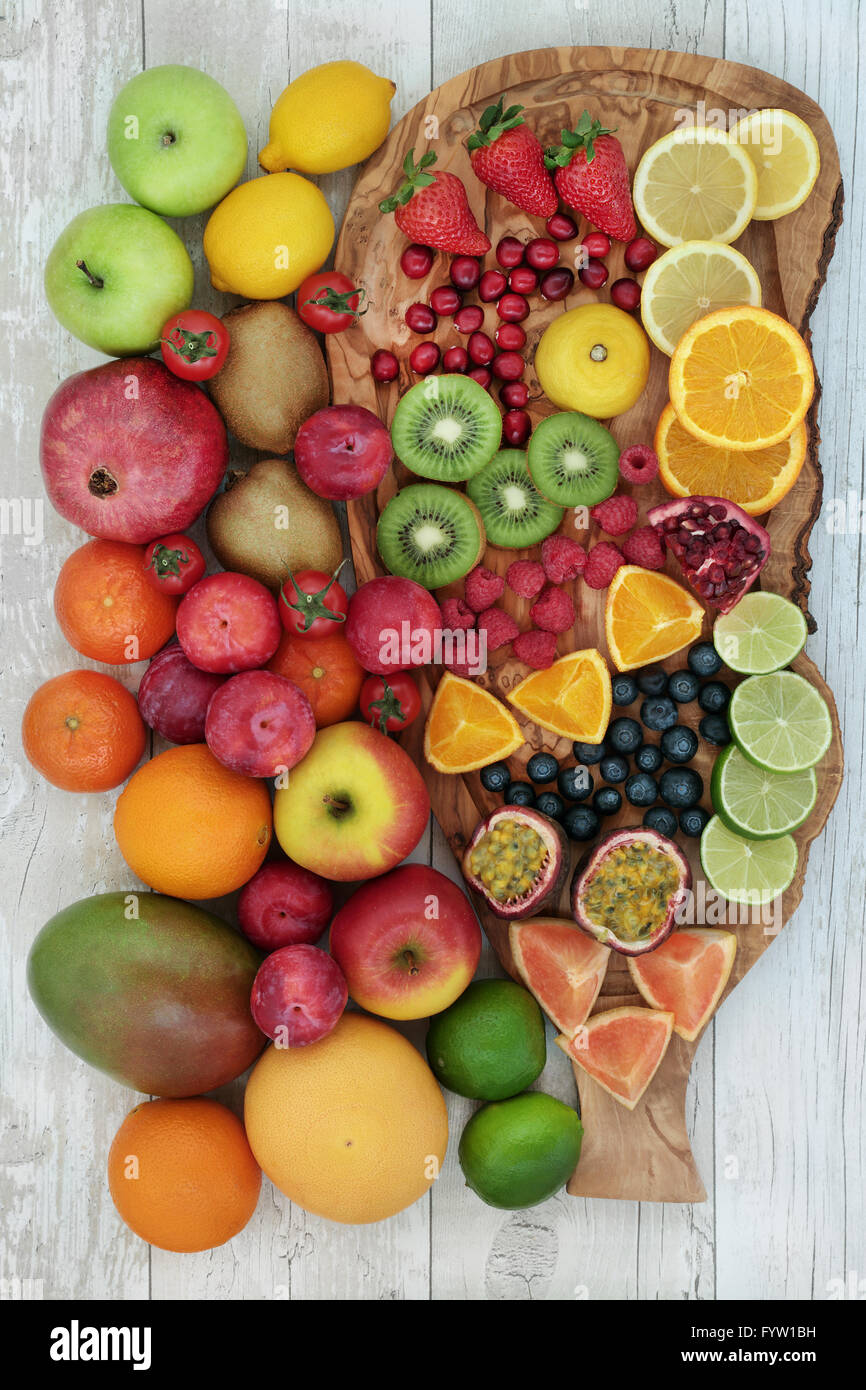 Large fresh fruit collection on an olive wood board over distressed ...