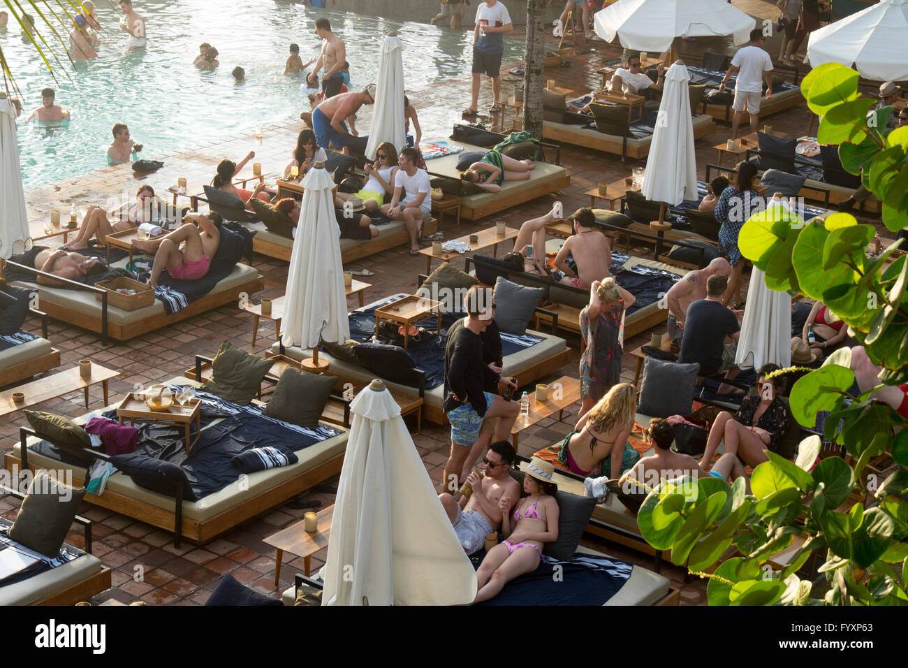 Tourists lounging on day beds around a swimming pool Stock Photo - Alamy