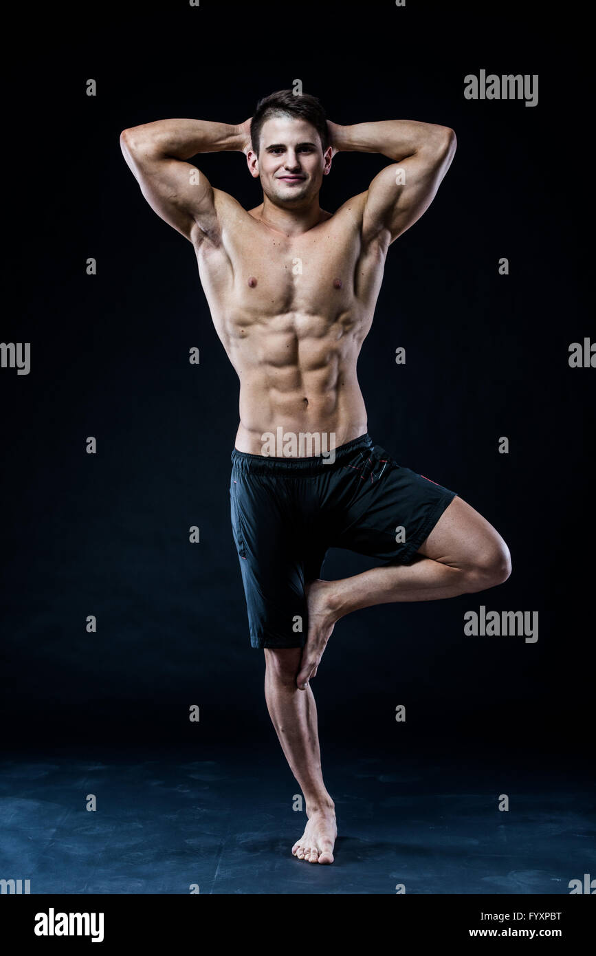 Muscular man balancing on the one leg feeling relaxed dark background ...