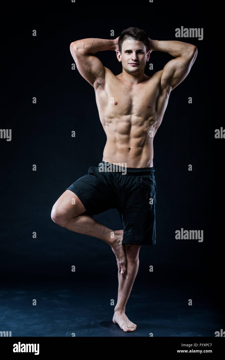 Muscular man balancing on the one leg feeling relaxed dark background ...