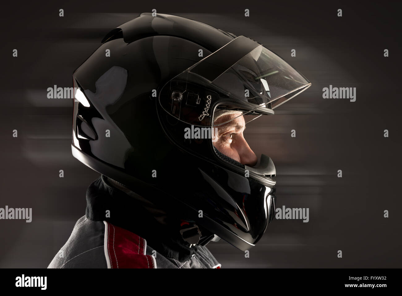 Racing driver posing with helmet isolated in black Stock Photo - Alamy