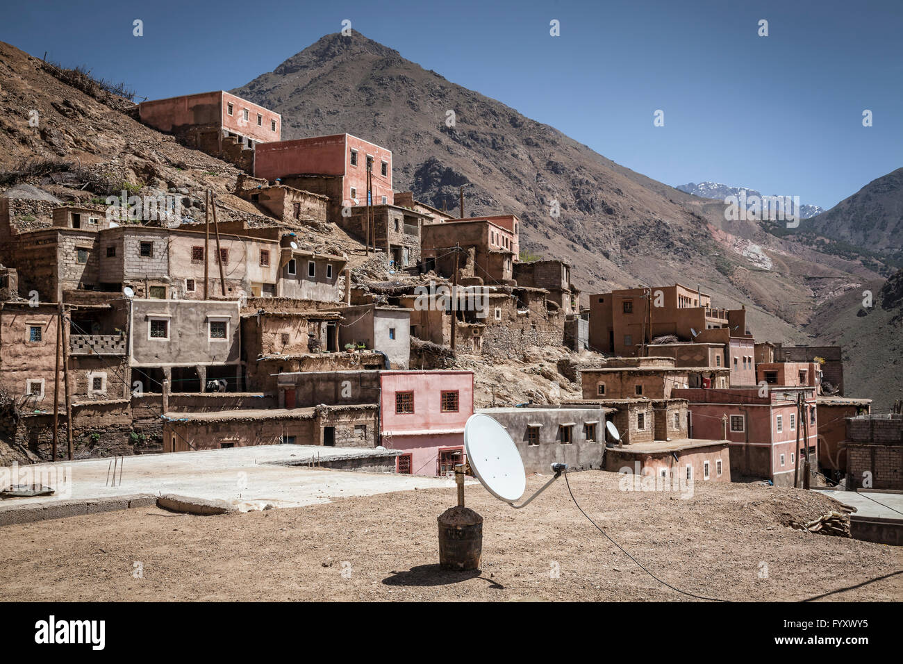 A satellite dish with a backdrop of traditionally built adobe houses in ...