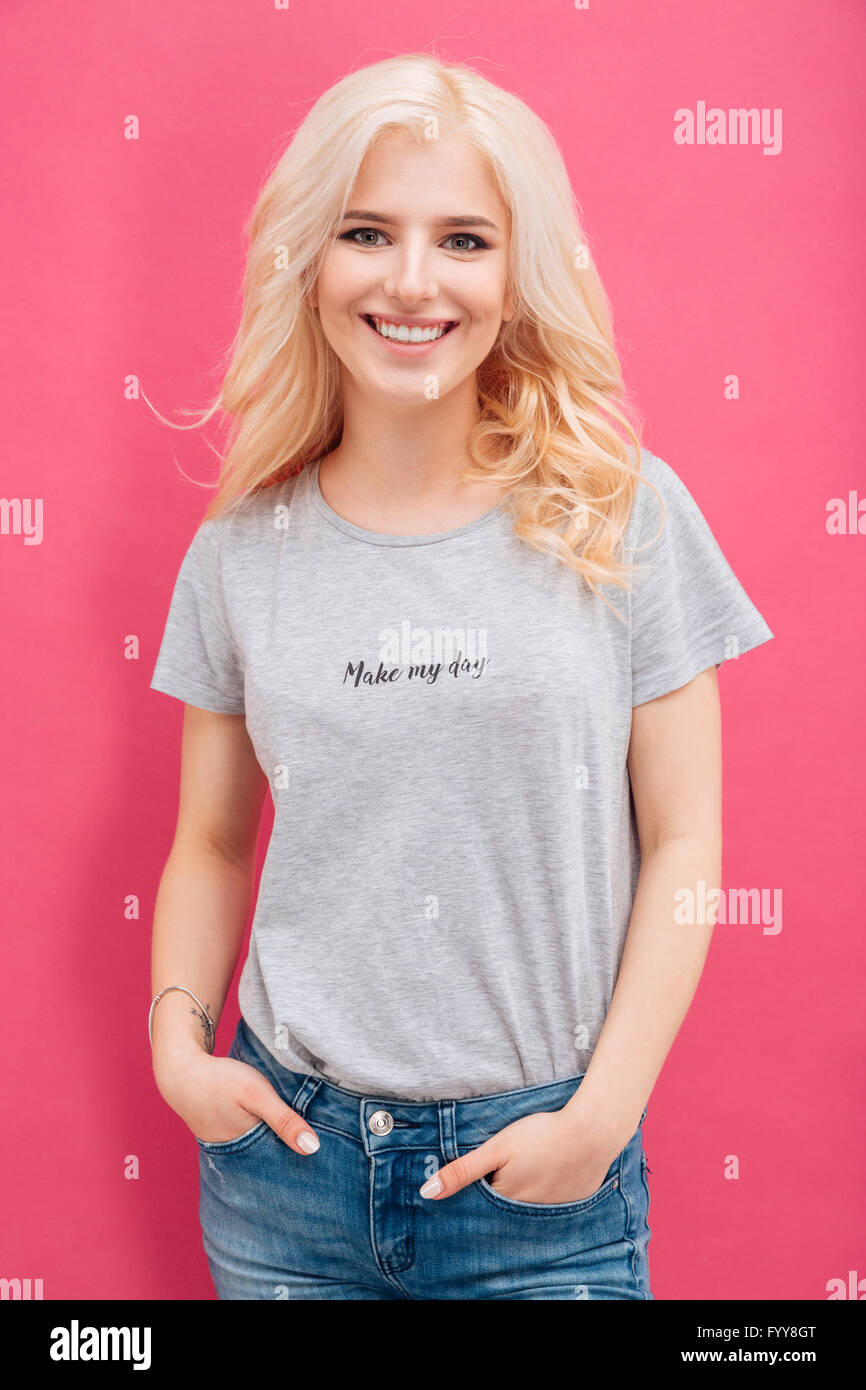 Smiling Attractive Woman Standing Over Pink Background And Looking At