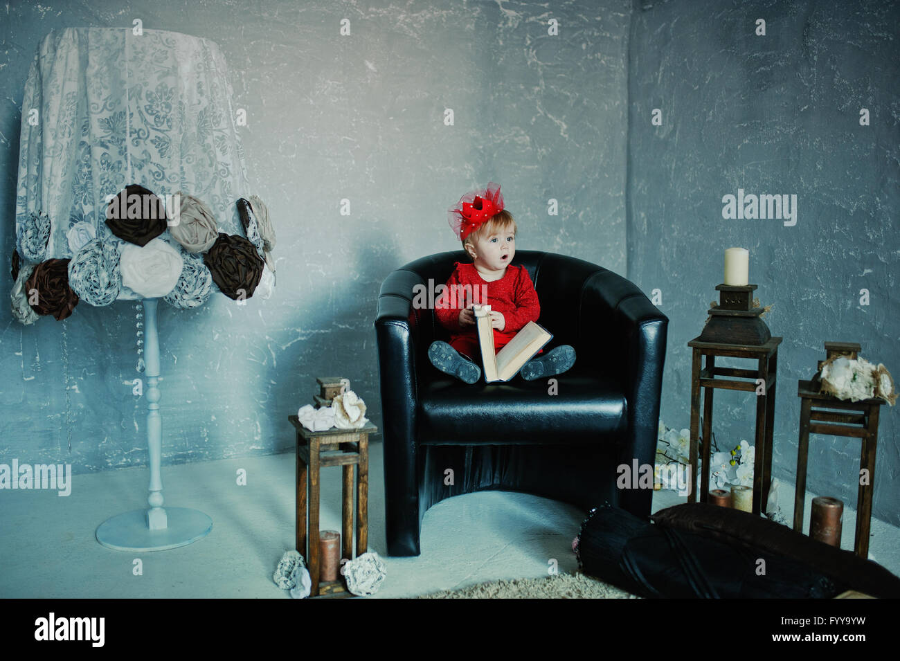 Little cute princess girl with a surprised face sitting on a chair and ...