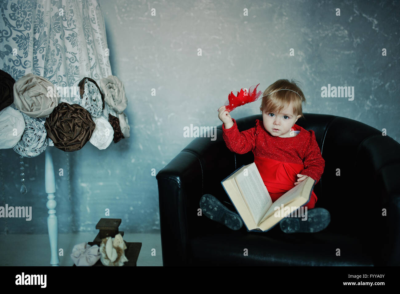 Little cute princess girl sitting on a chair, read old book and takes ...