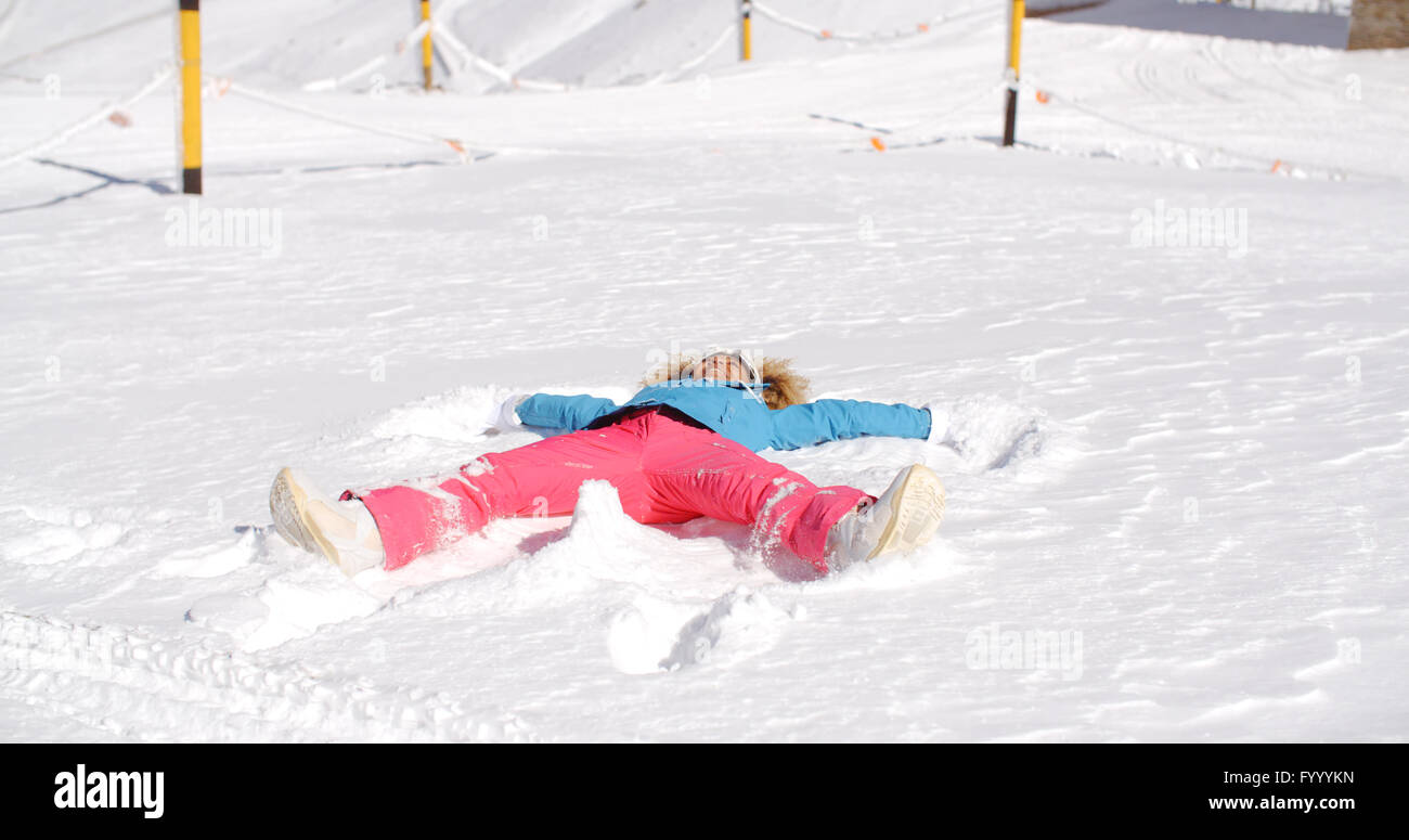 Young woman making a angel in white snow Stock Photo - Alamy
