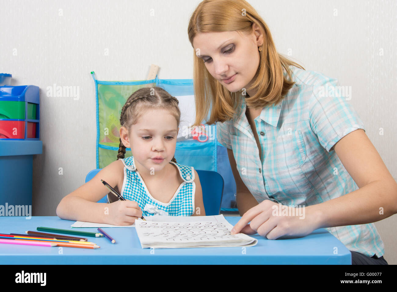 Mentor shows five children to write letters correctly Stock Photo - Alamy