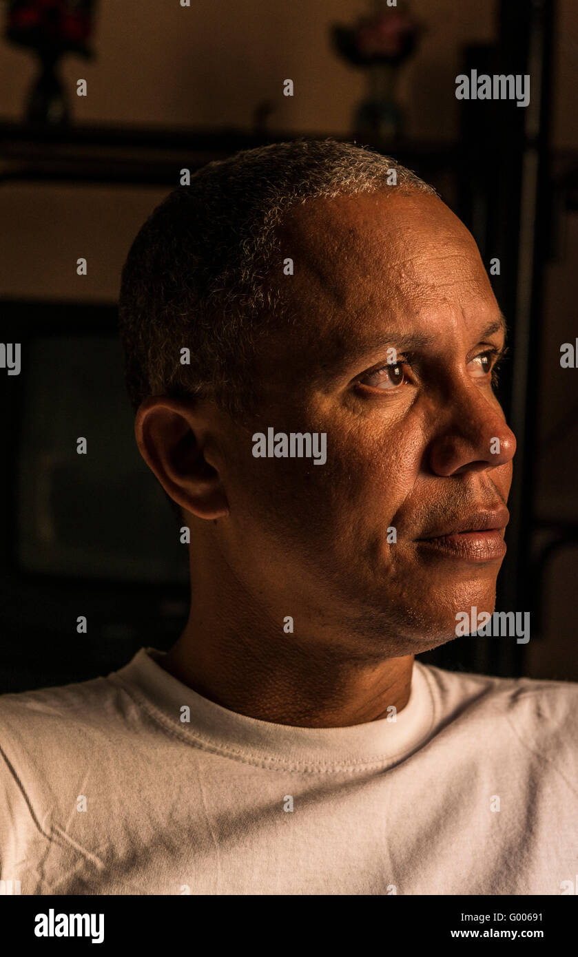 Portrait of a young Afro Cuban man wearing a white shirt, in window ...