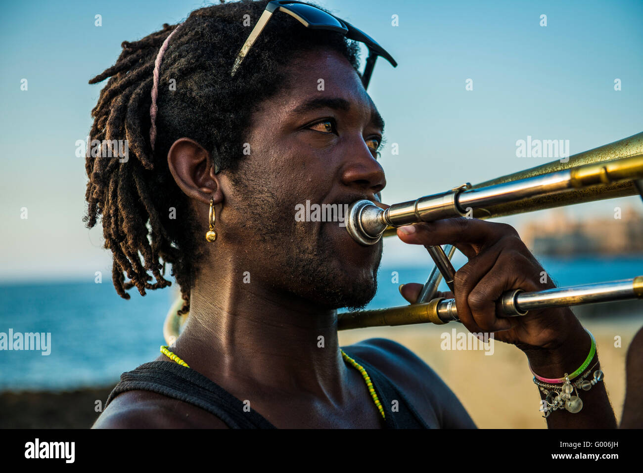 Afro Cuban man with dreadlocked hair plays trombone on the Malecón ...