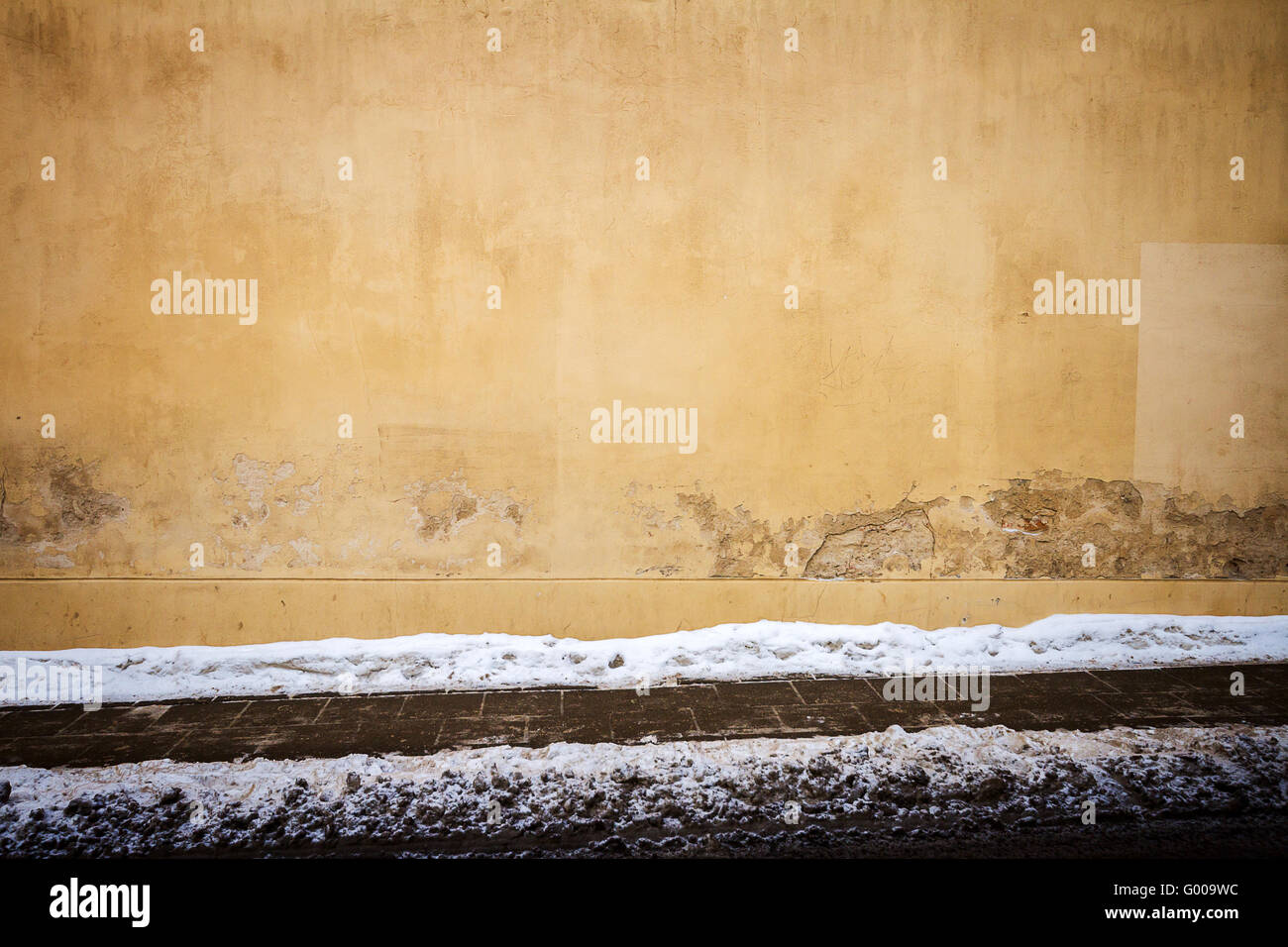 Yellow plaster street wall and ground covered with snow Stock Photo - Alamy