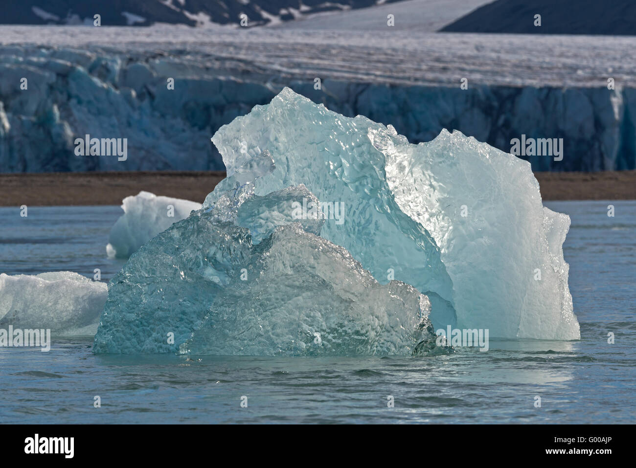 A clear, crystal like iceberg floating in front of the glacier at ...
