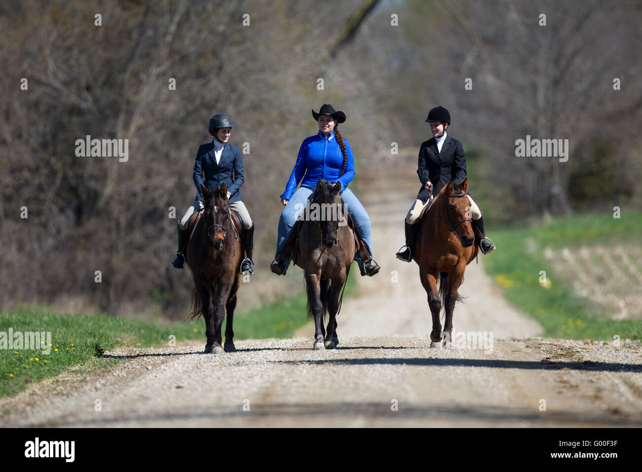 Three women riding horses together on a dirt road in the country Stock ...