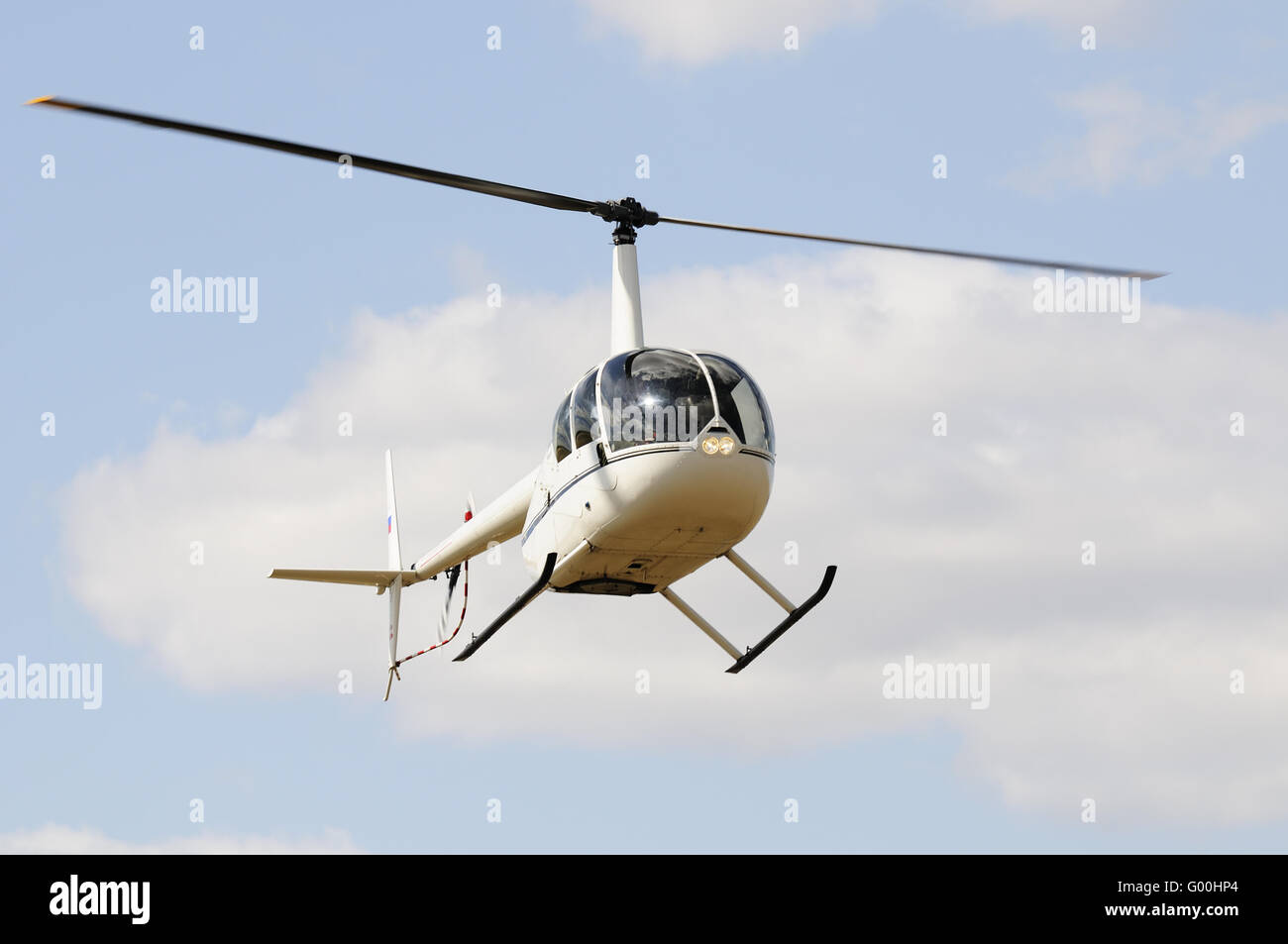 Light helicopter flying in blue cloudy sky Stock Photo - Alamy