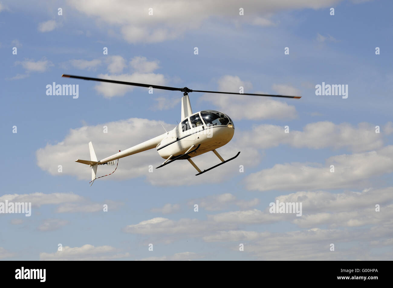 Light helicopter flying in blue cloudy sky Stock Photo - Alamy