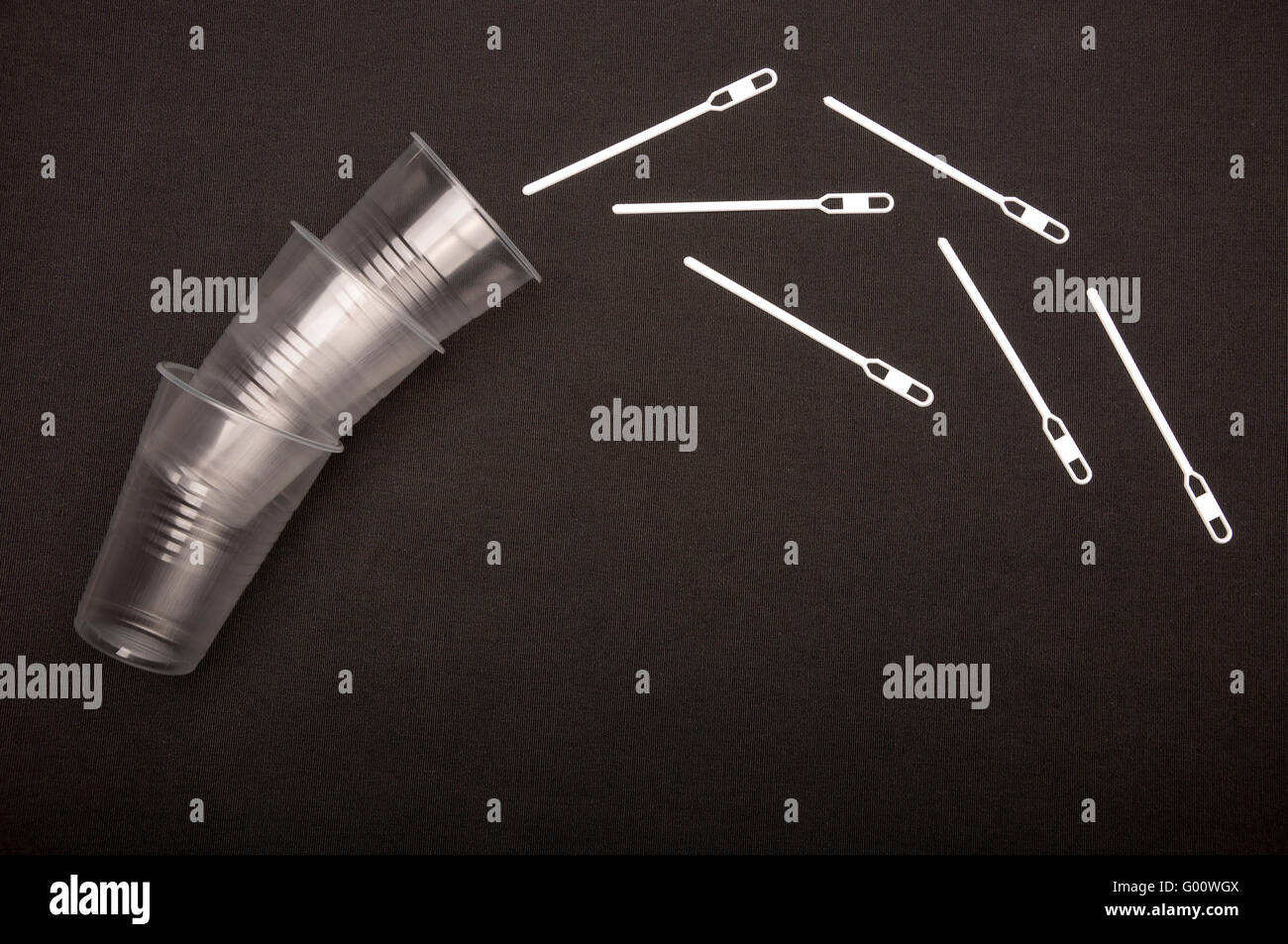 White stirring sticks near clear plastic cups on black background ...